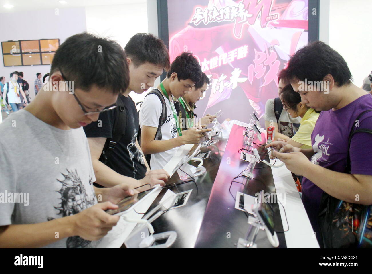 --FILE--Visitors play mobile games on tablet PCs and smartphones during ...