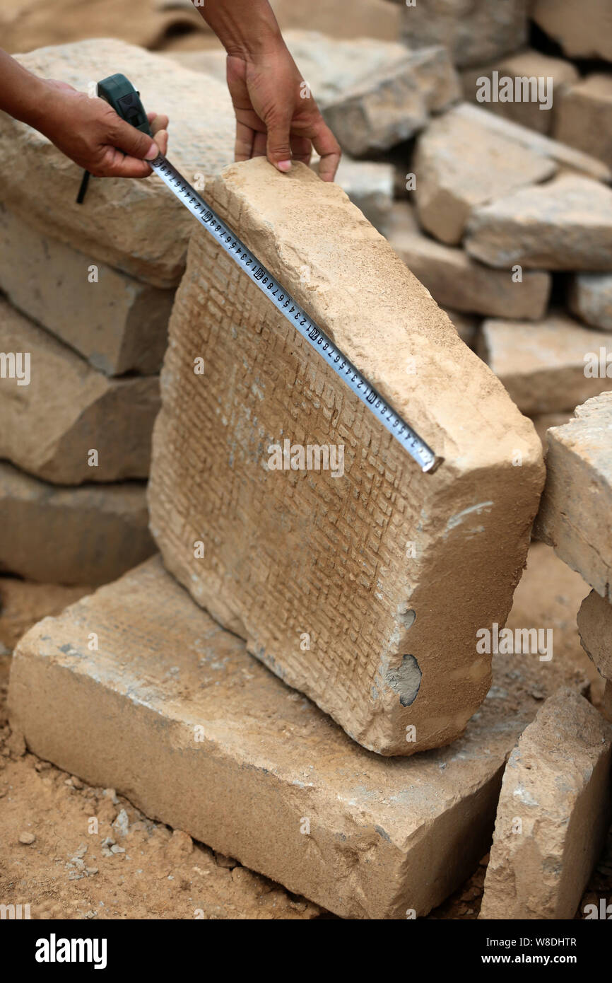 A Chinese archaeologist measures the length of a brick unearthed from ...