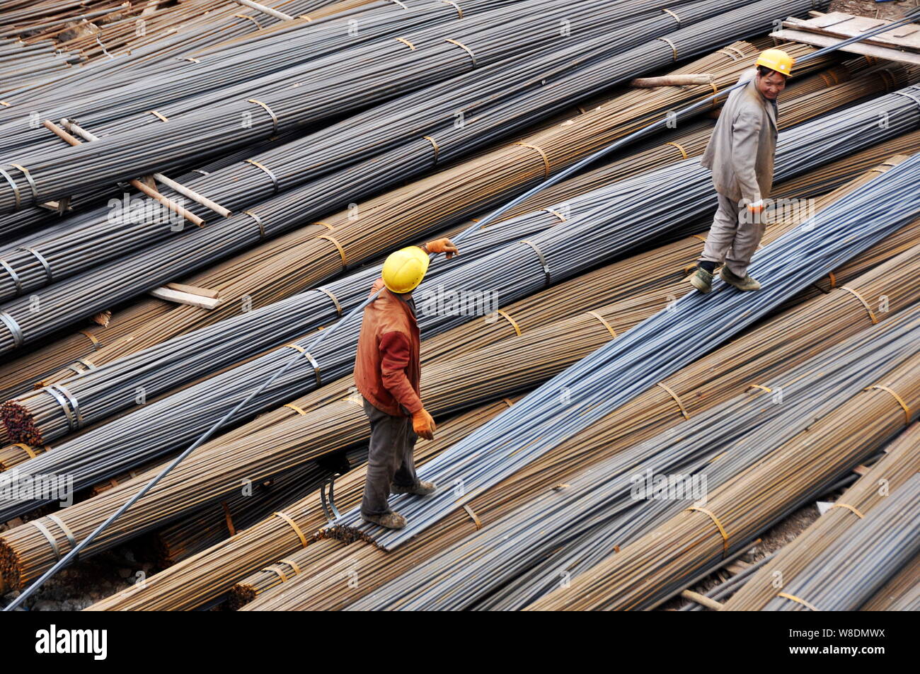 --FILE--Chinese workers carry reinforcing steel rods at the ...