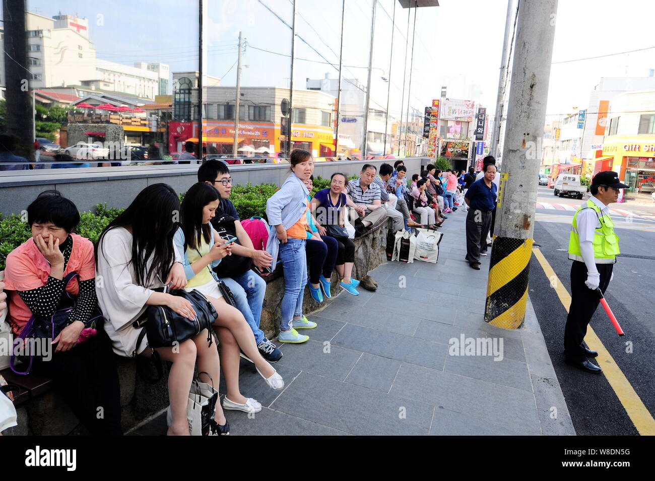 --FILE--Chinese tourists rest along a street outside a duty free store ...
