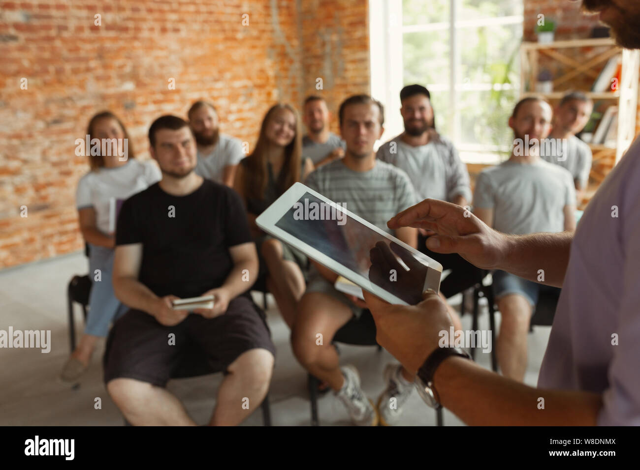 Male speaker giving presentation at university workshop. Audience or conference hall. Using ...