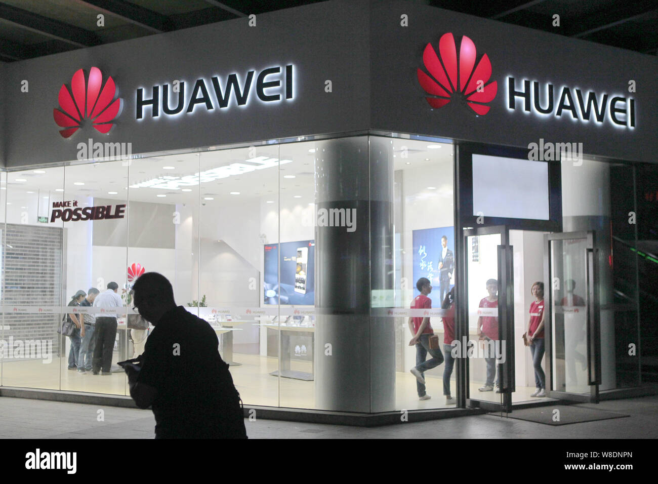 A pedestrian walks past a store of Huawei at night in Shenzhen city ...