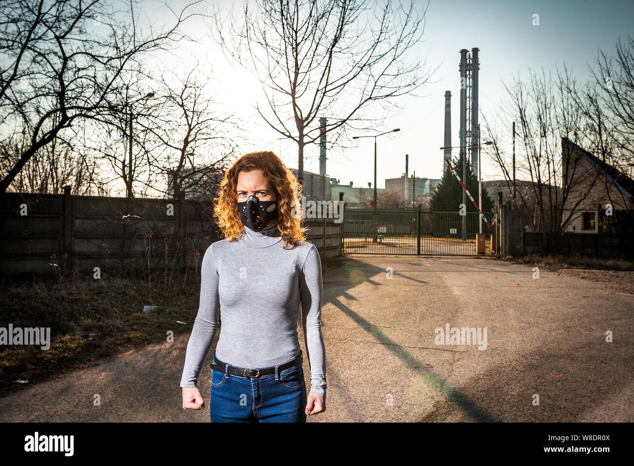 Angry woman activist wear mask standing in front of a gas factory ...