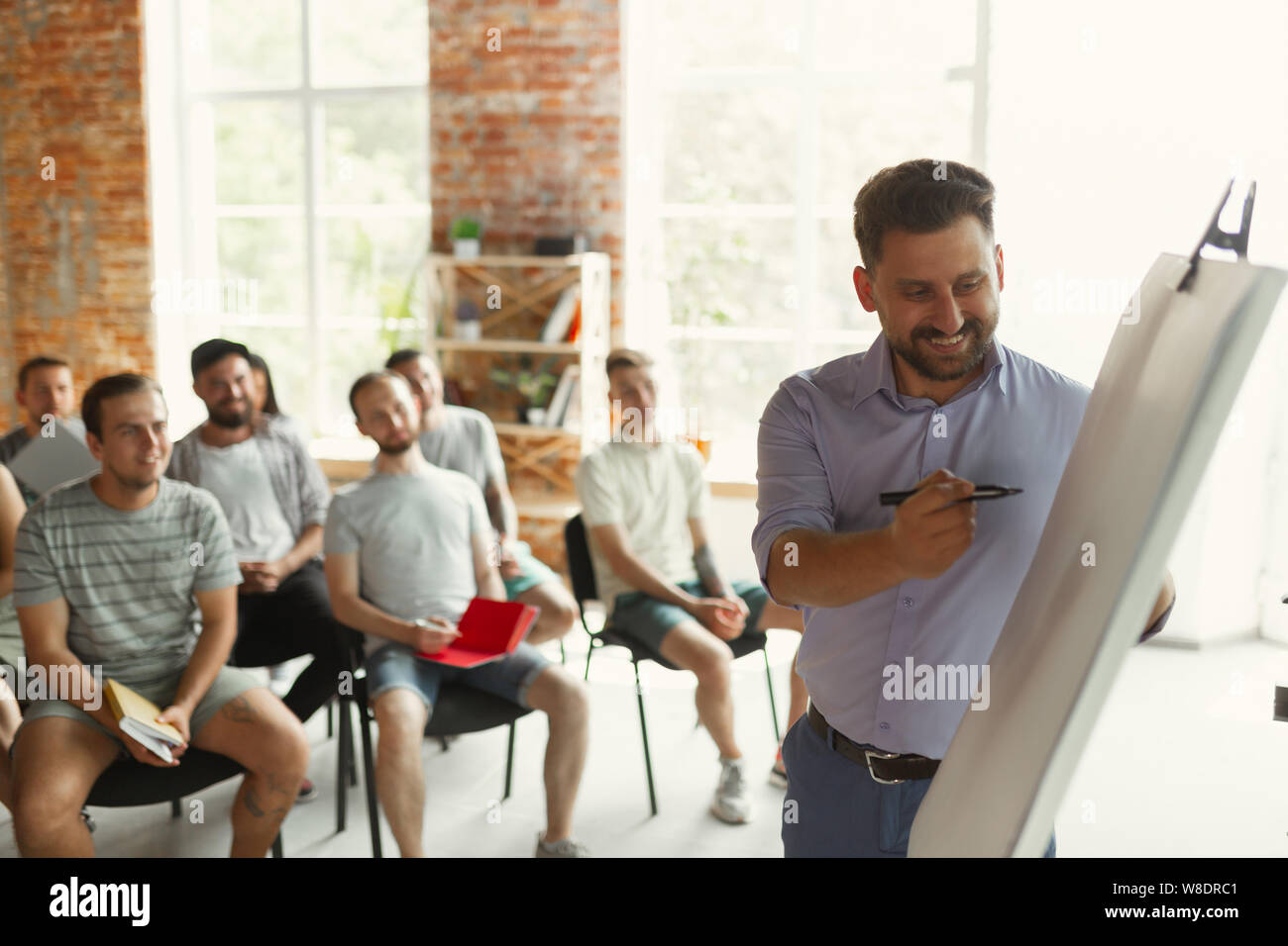 Male speaker giving presentation at university workshop. Audience or ...