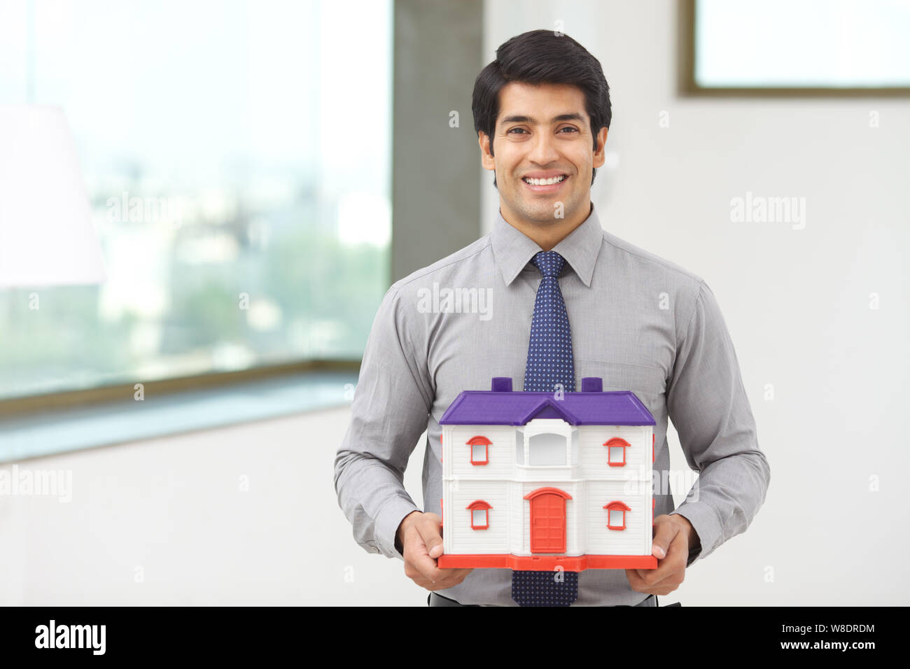 Real estate agent holding a miniature house Stock Photo - Alamy