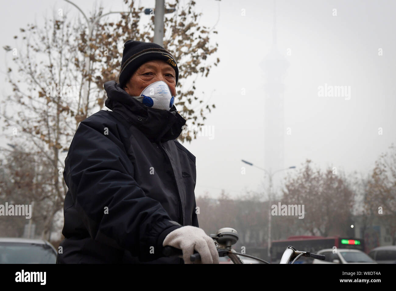A Chinese cyclist wearing a face mask against air pollution pushes his ...