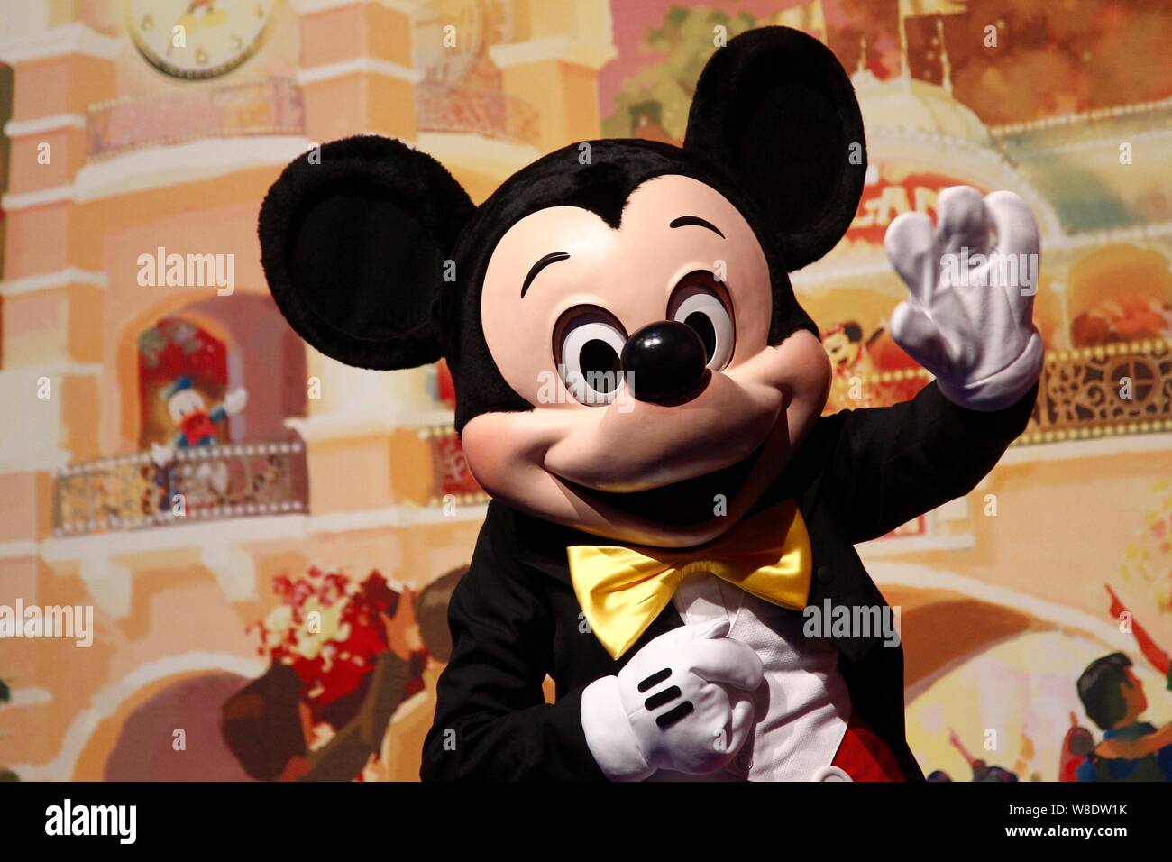 An entertainer dressed in a costume of Micky Mouse waves during a ...