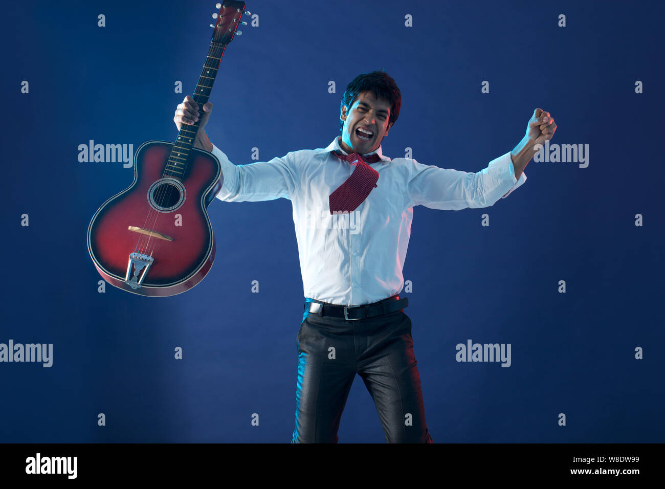 Young man playing a guitar and punching the air Stock Photo - Alamy