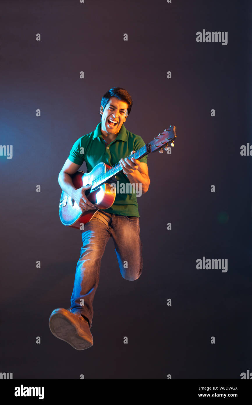 Young man jumping in air and playing guitar and singing Stock Photo - Alamy
