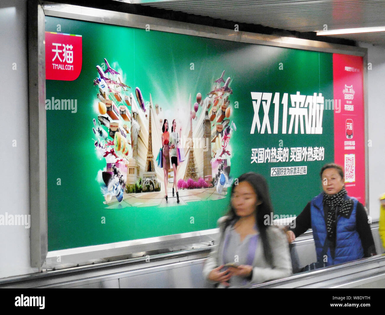 --FILE--Passengers pass by an advertisement for the Tmall 11.11 online shopping festival of ...