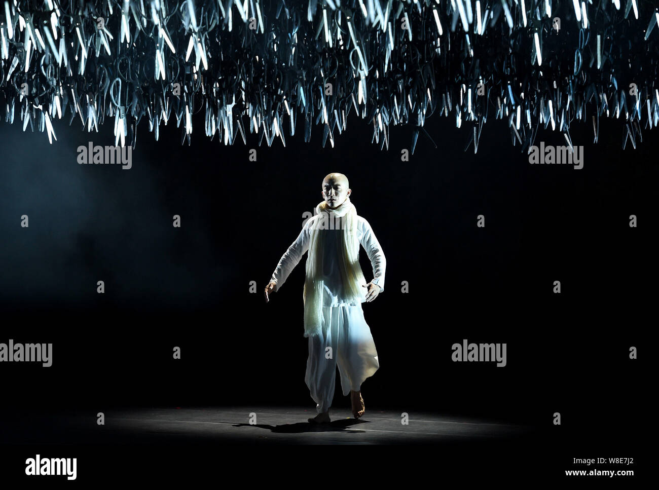 A dancer performs under thousands of hanging scissors during the debut ...