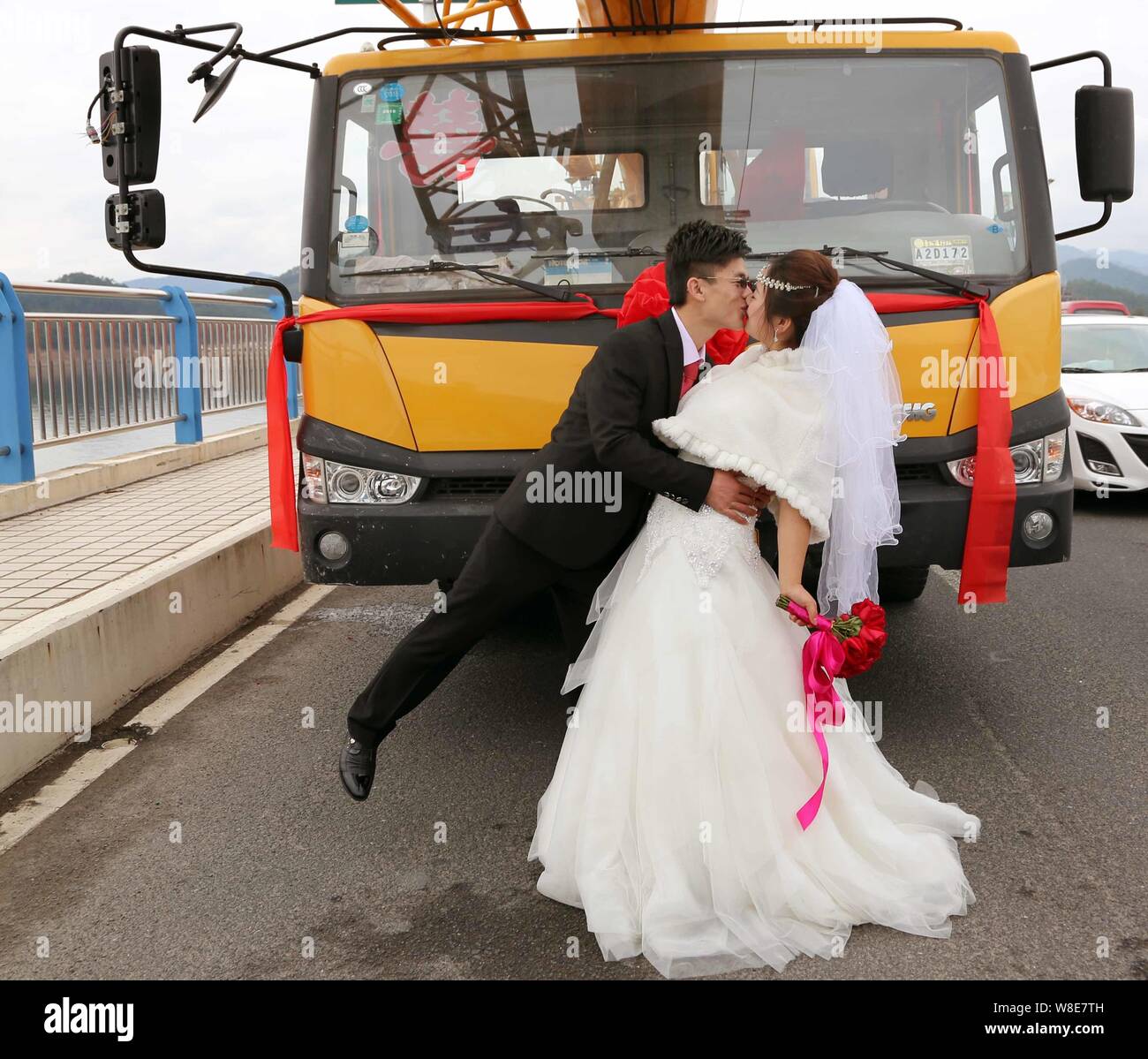 Chinese groom Xie Jiangjian, left, kisses his bride in front of a crane ...