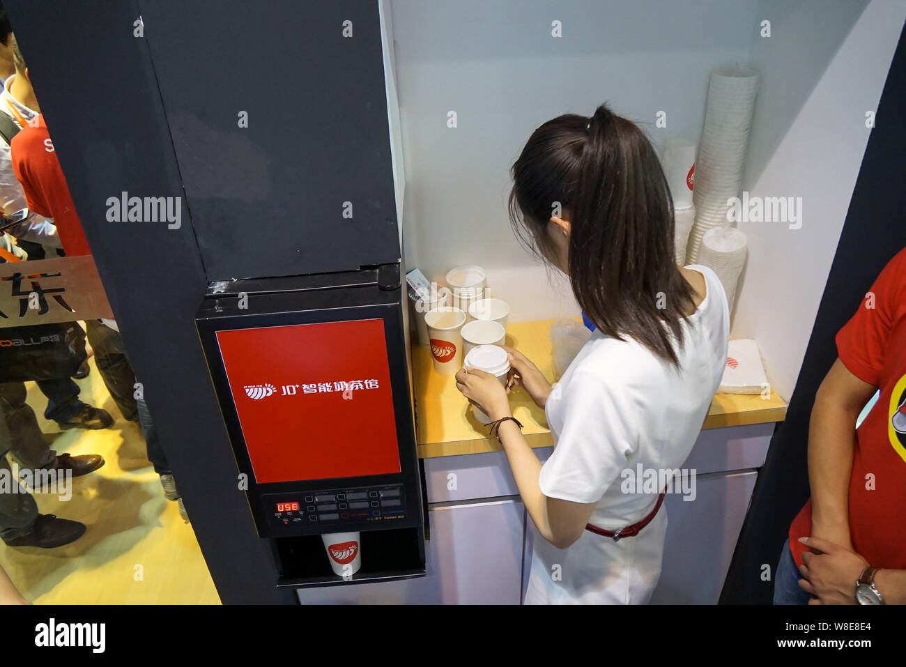 A Chinese employee makes milk tea for visitors at a "JD+ smart milk tea ...