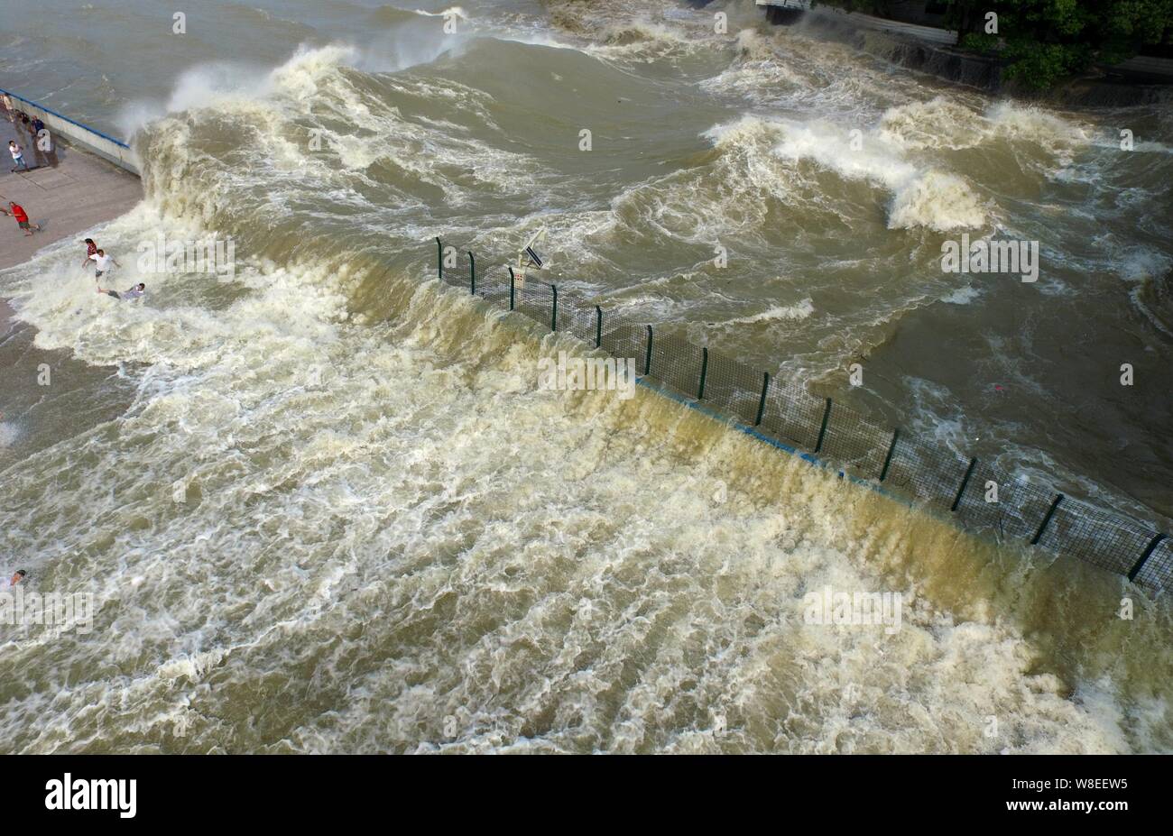 Visitors and local residents run as waves from a tidal bore surge past ...