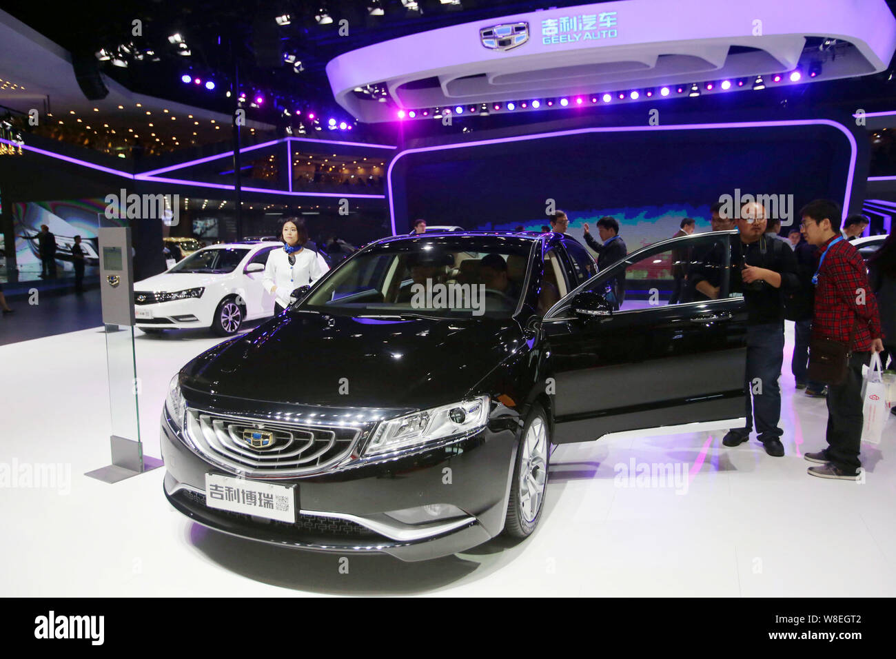 --FILE--Visitors look at or try out a Geely GC9 on display during the ...