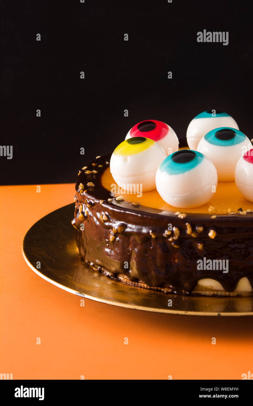 Halloween cake with candy eyes decoration on orange and black ...