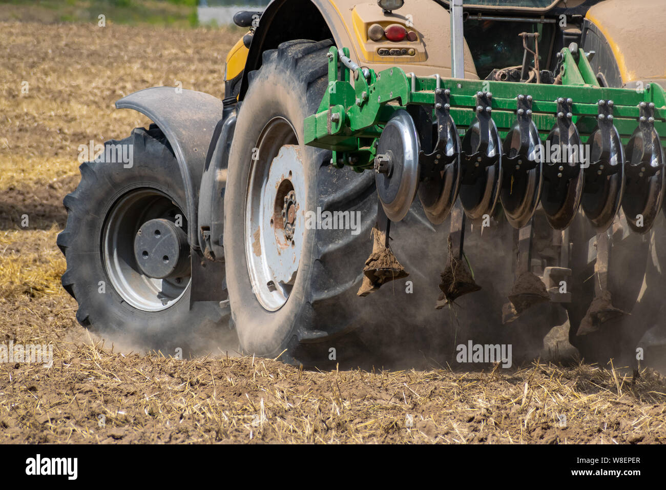 Yellow tractor with the cultivator turning on the field rear view Stock ...