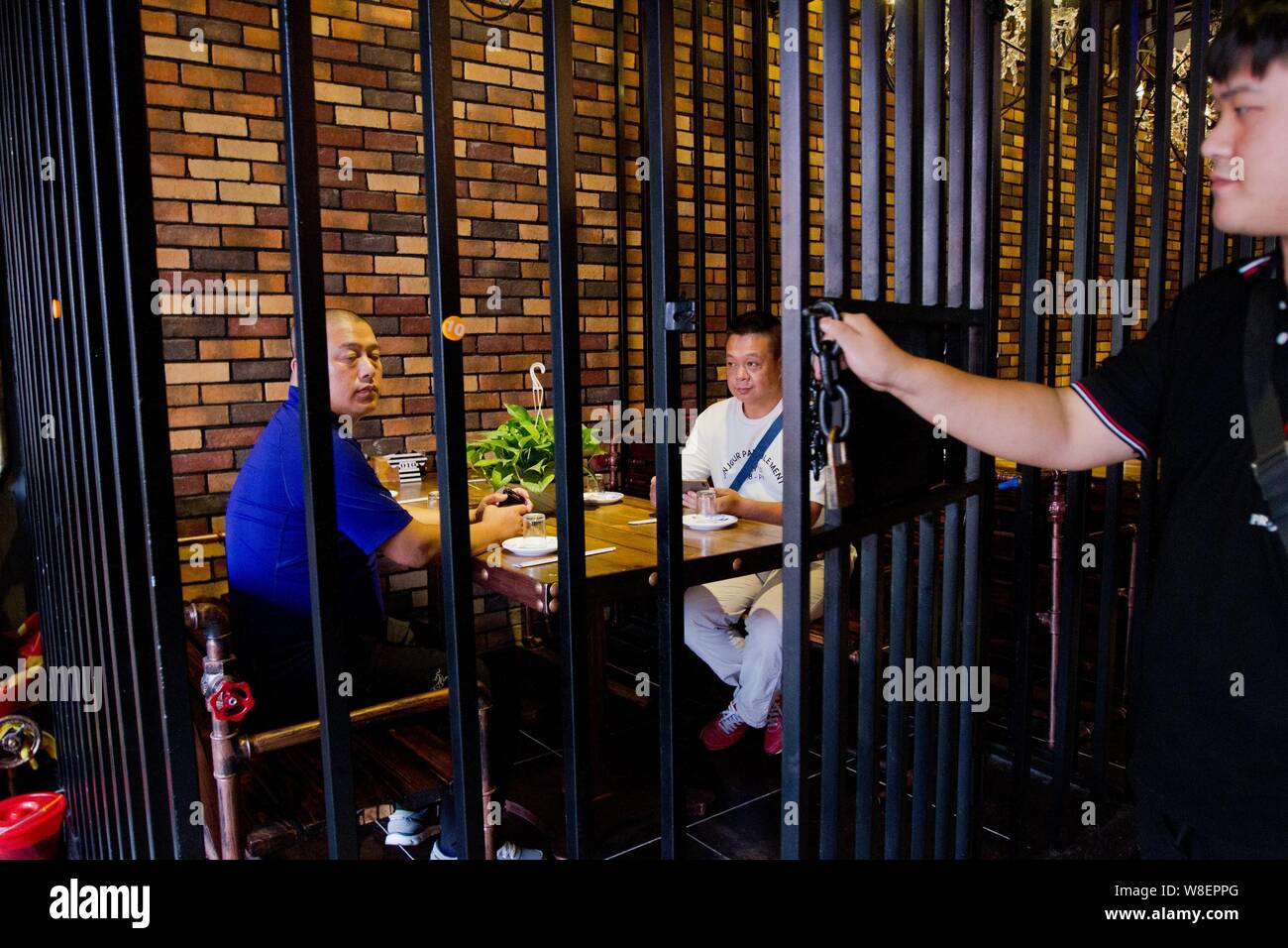 A waiter locks the door hatch of a dining room at a prison-themed ...