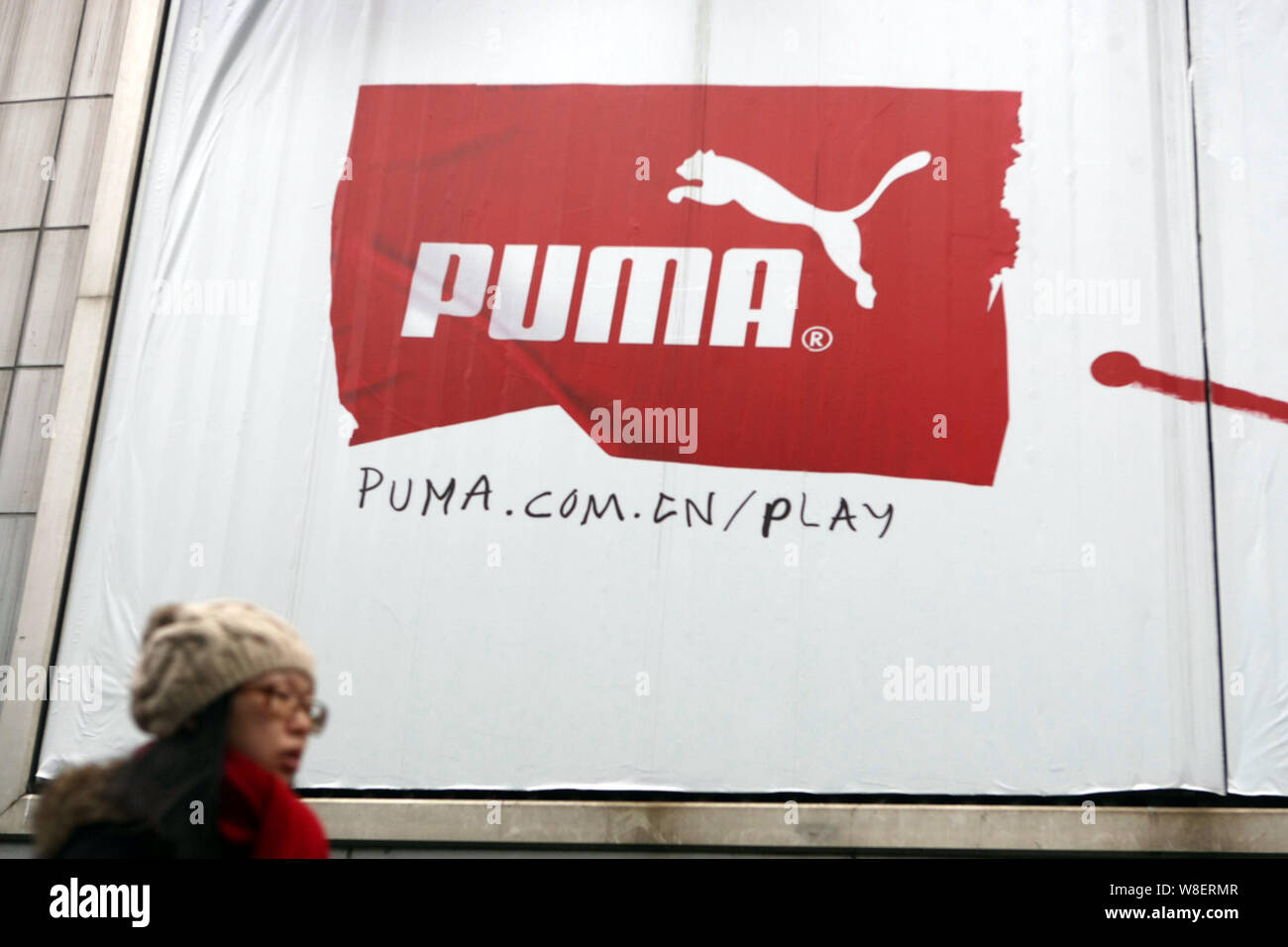 --FILE--A pedestrian walks past an advertisement for Puma in Shanghai ...