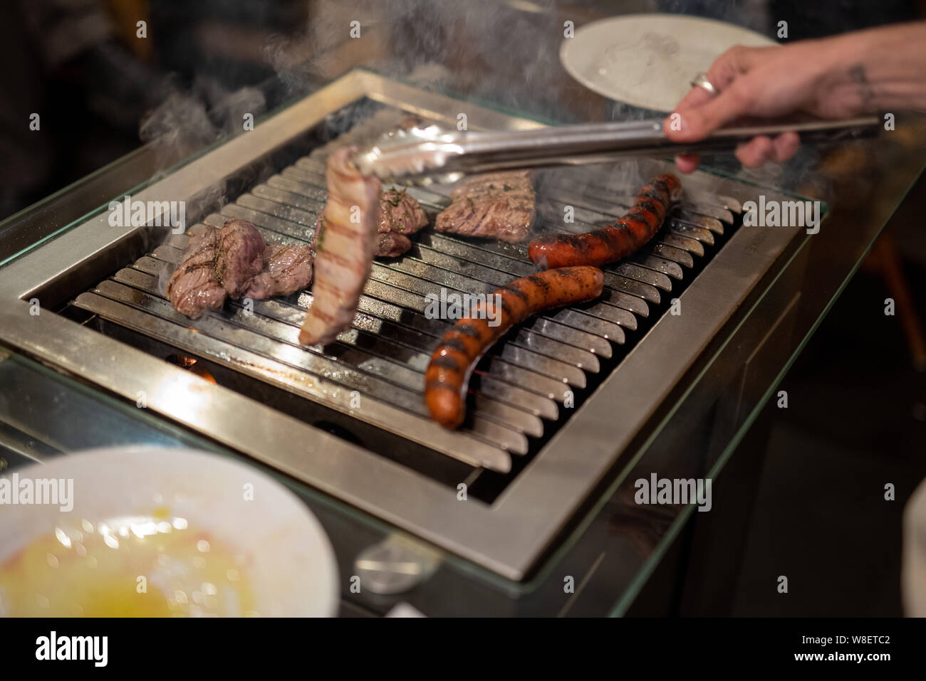 different types of meat, beef steaks and pork sausages, cooked on a ...