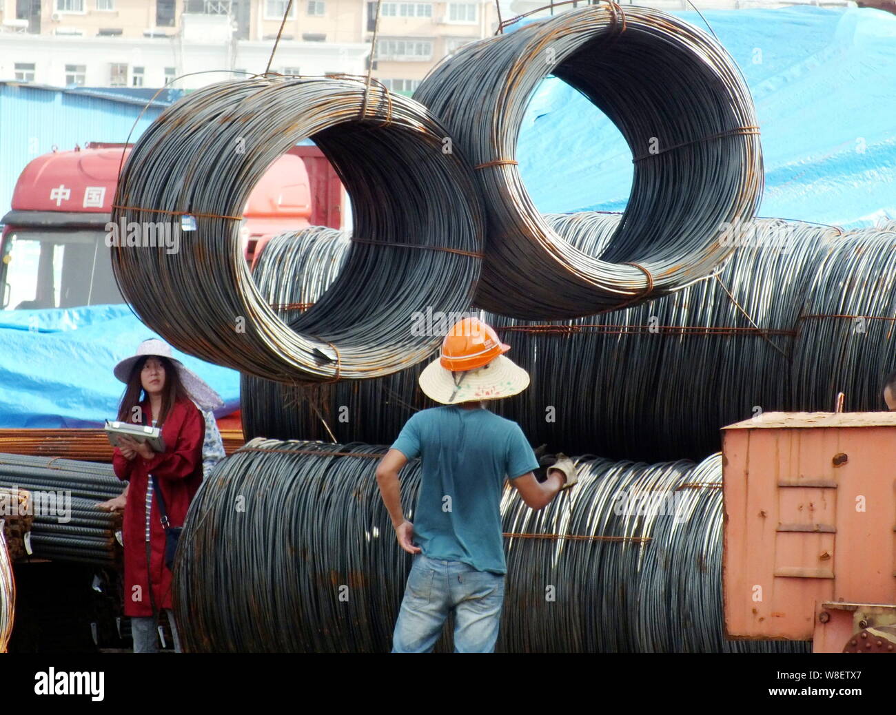 --FILE--Chinese workers watch rolls of coiled steel rods being lifted ...
