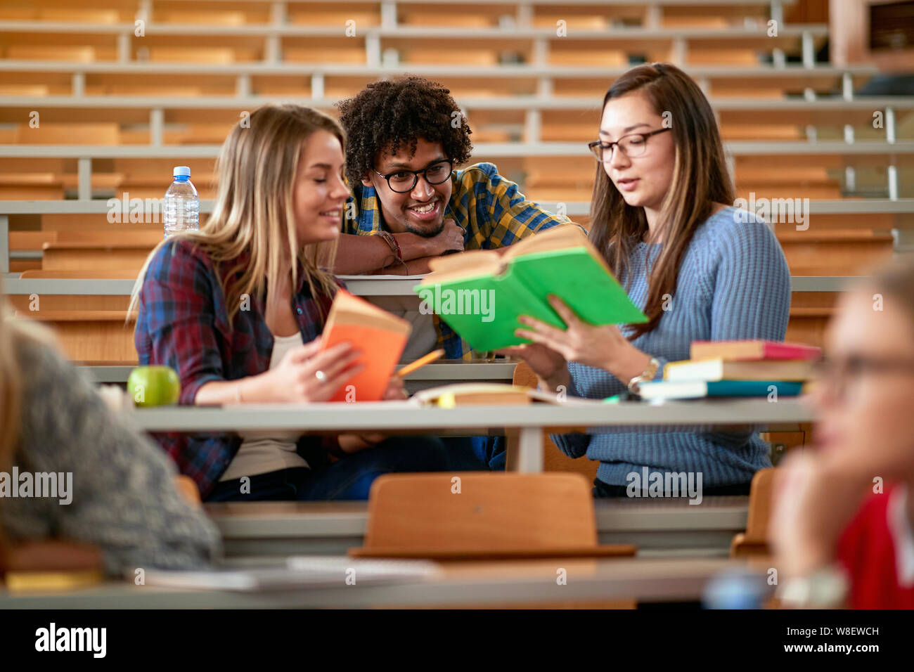 Smiling young student’s discussion and writing together at college ...