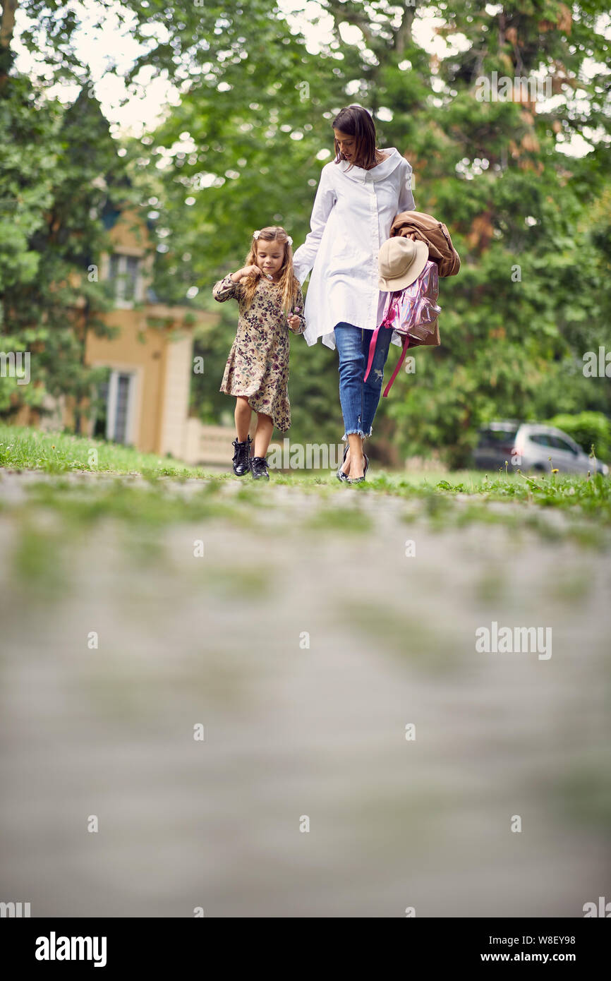 first day at school over, happy parent and girl going home from school ...