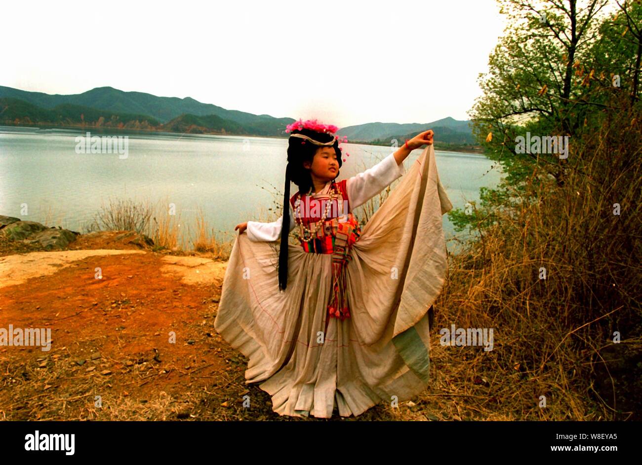 A Mosuo minority young girl dressed in traditional clothes dances at ...