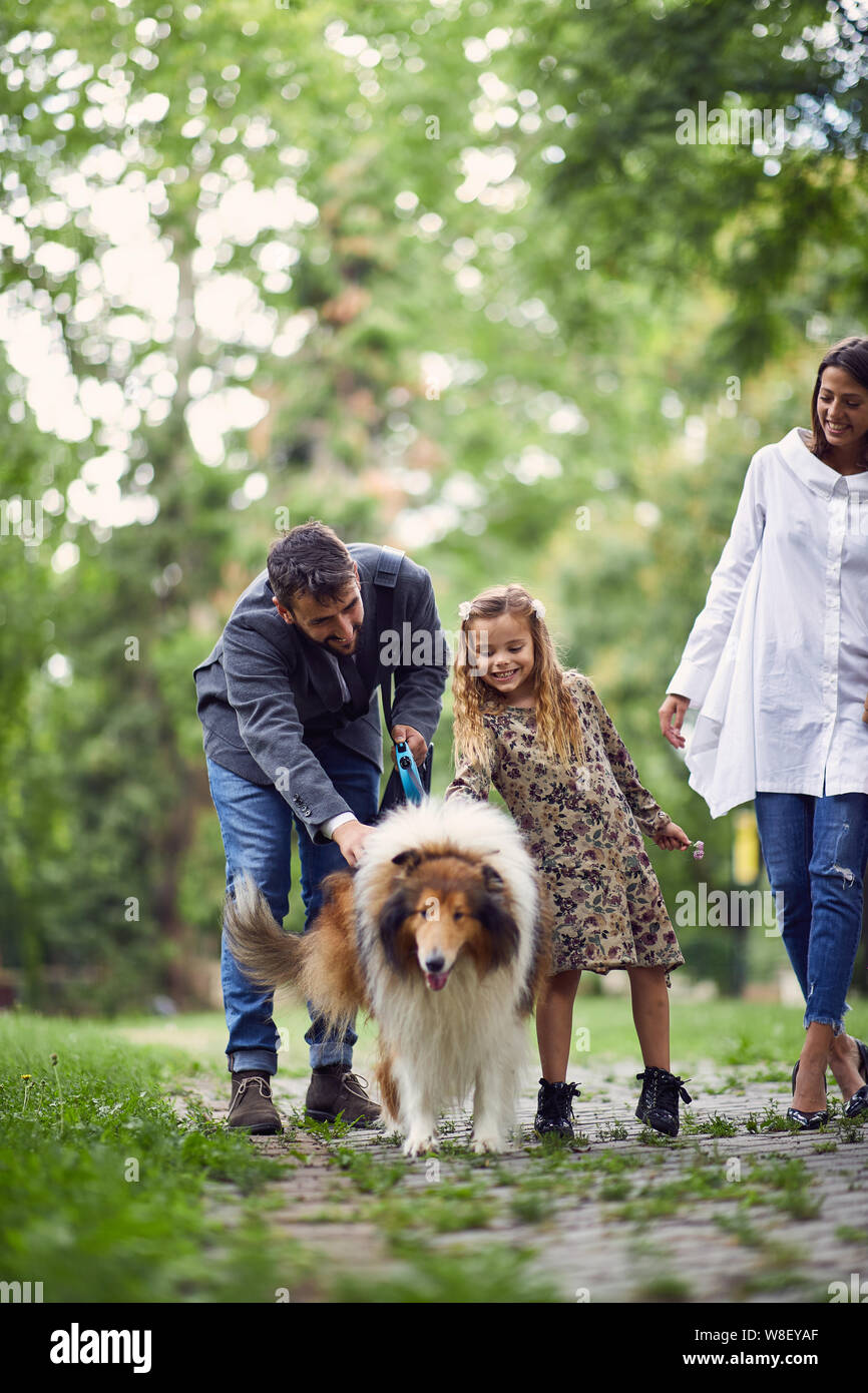 smiling family is taking out a dog for a walk in to the park Stock ...