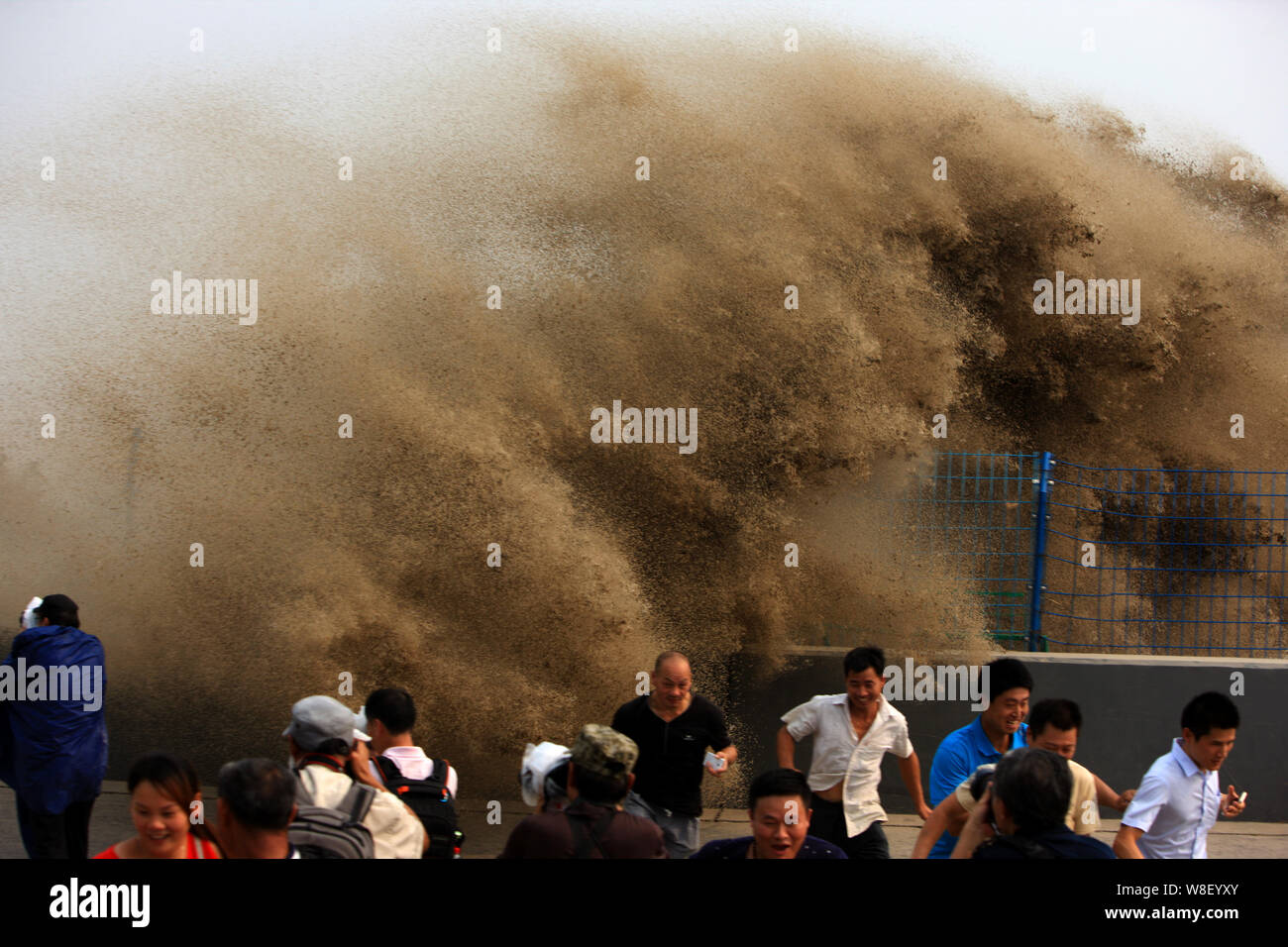 Visitors and local residents run away as waves from a tidal bore surge ...