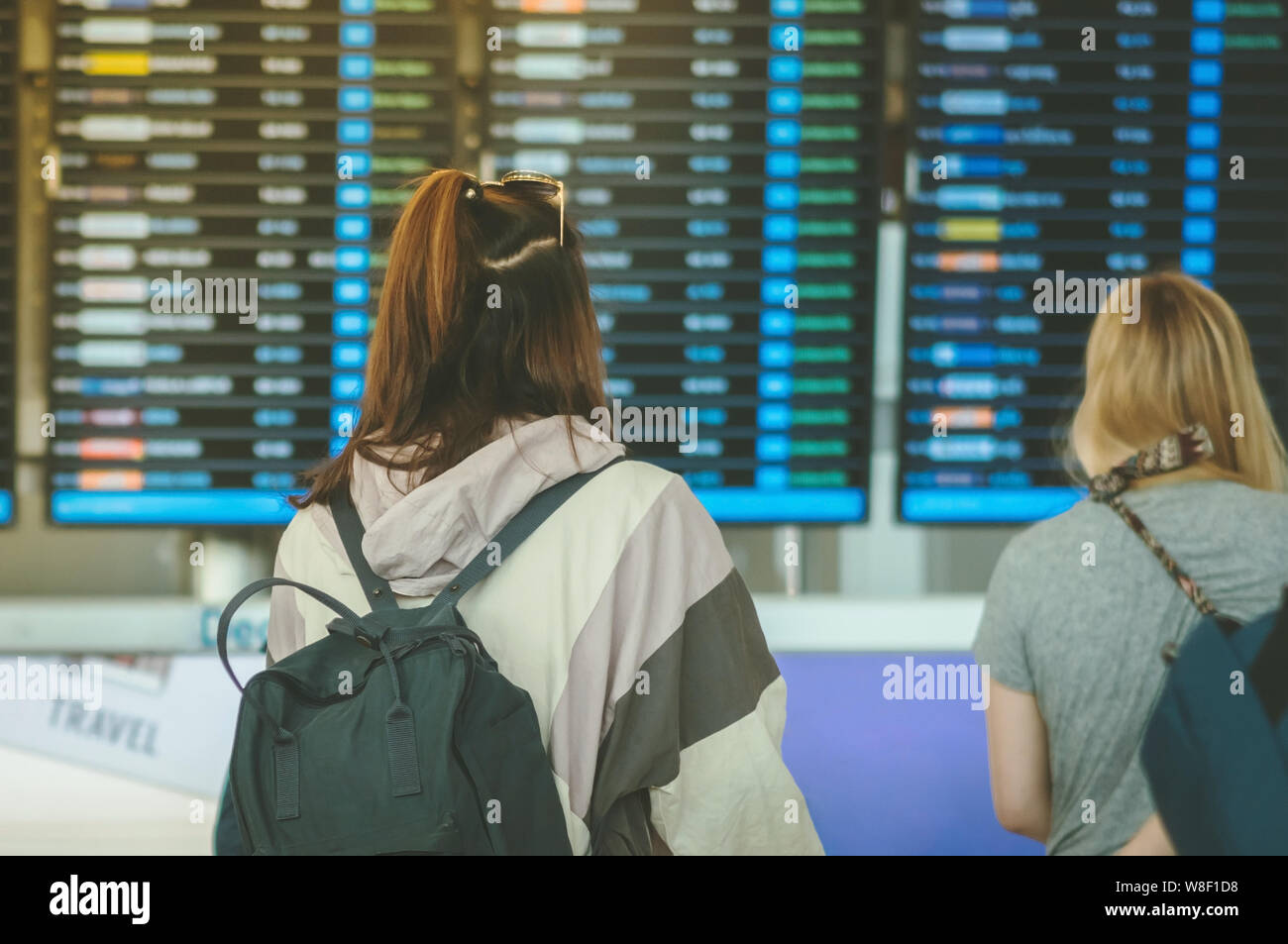 Passengers looking at the flight information board and checking their ...