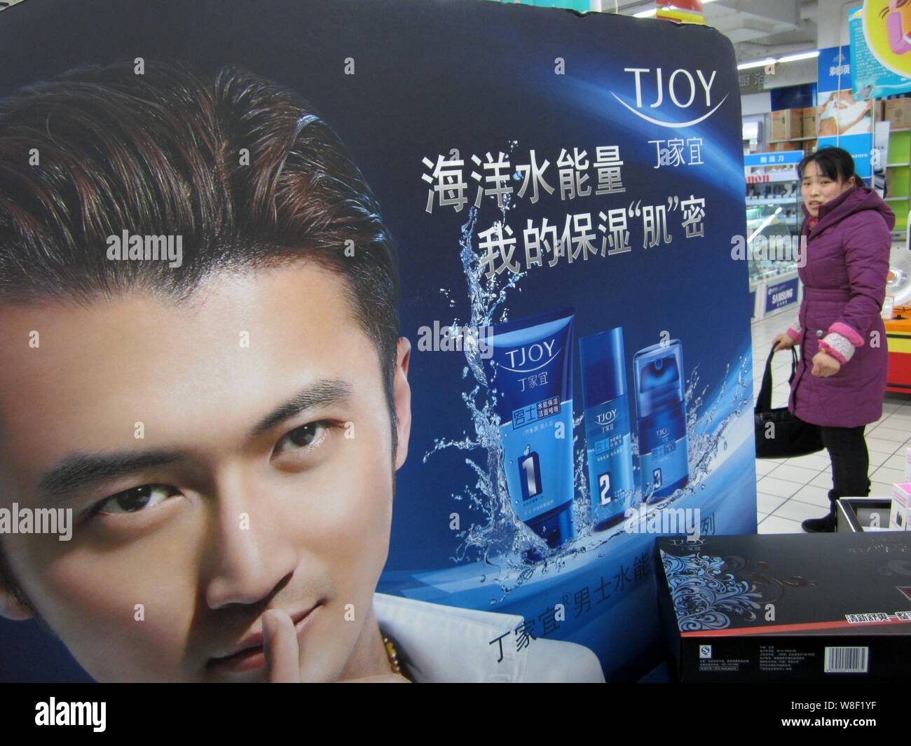--FILE--A Chinese customer walks past an advertisement for Tjoy ...