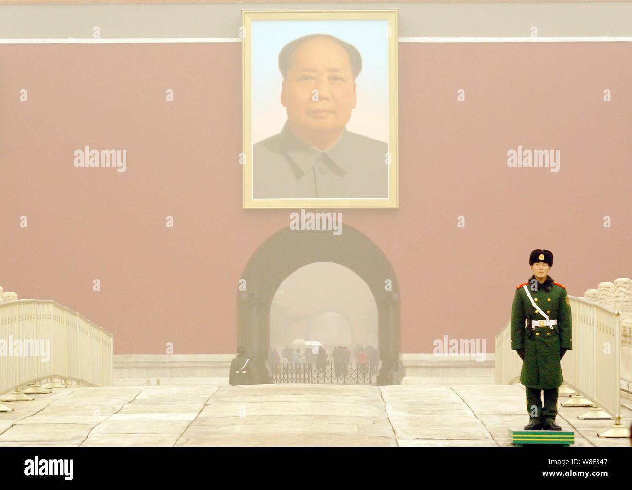 A Chinese paramilitary policeman stands guard in front of a portrait of ...