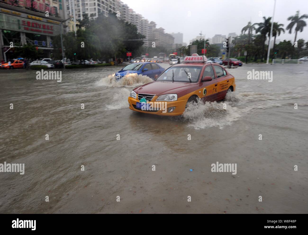 Cars drive on a flooded road in a heavy rain caused by Typhoon Mujigae ...