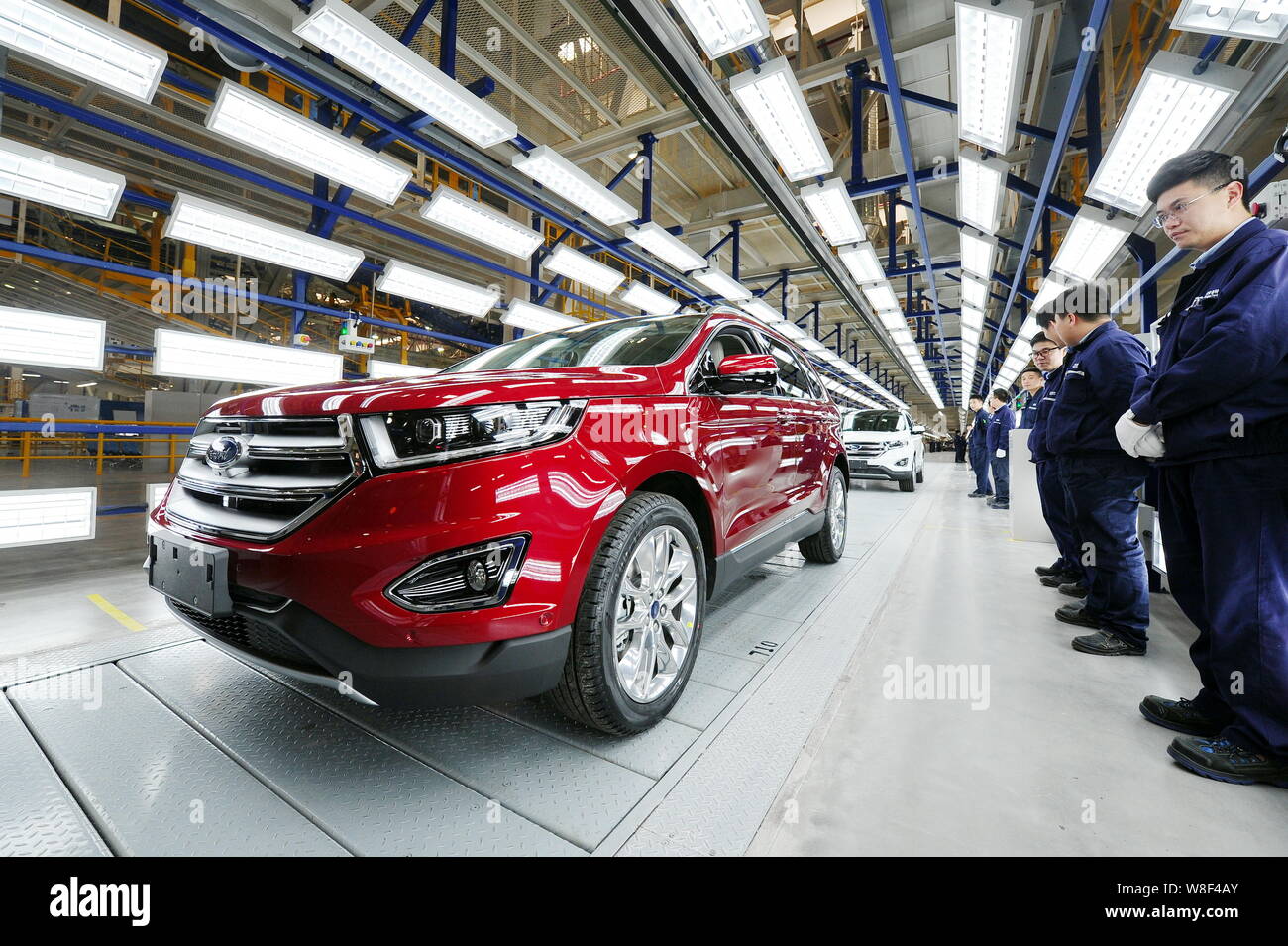 Chinese workers watch Ford SUVs passing through the assembly line at ...