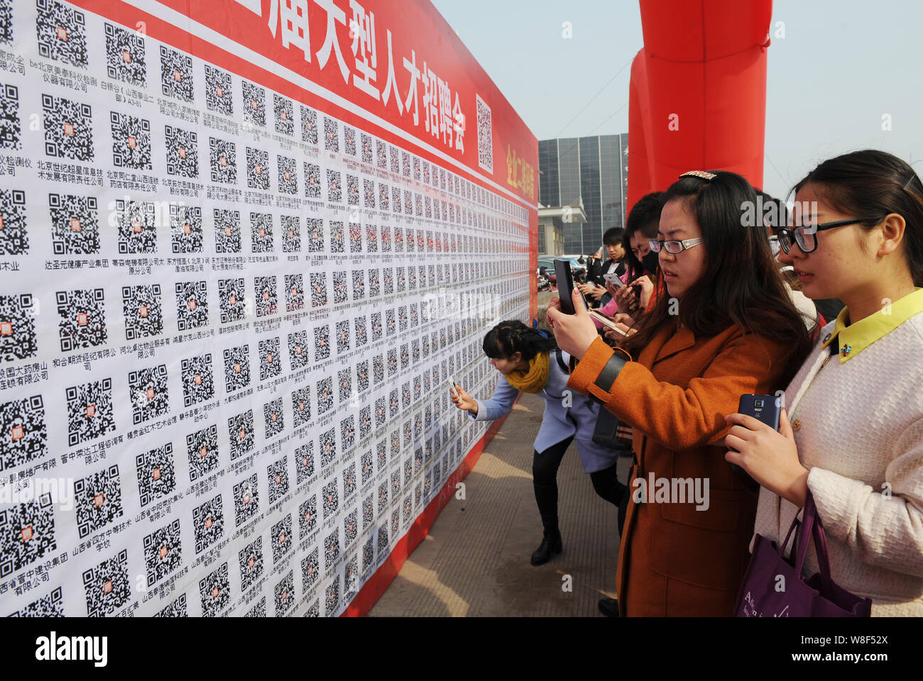 Job seekers scan QR codes on a big billboard of available jobs to ...