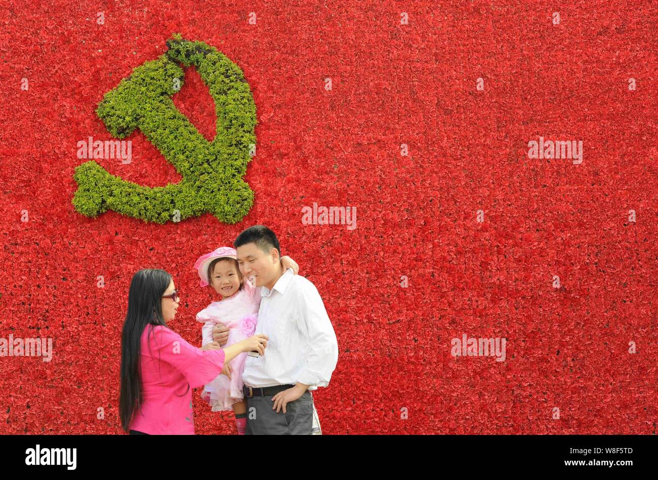 --FILE--A family of three is pictured in front of a Communist party of ...