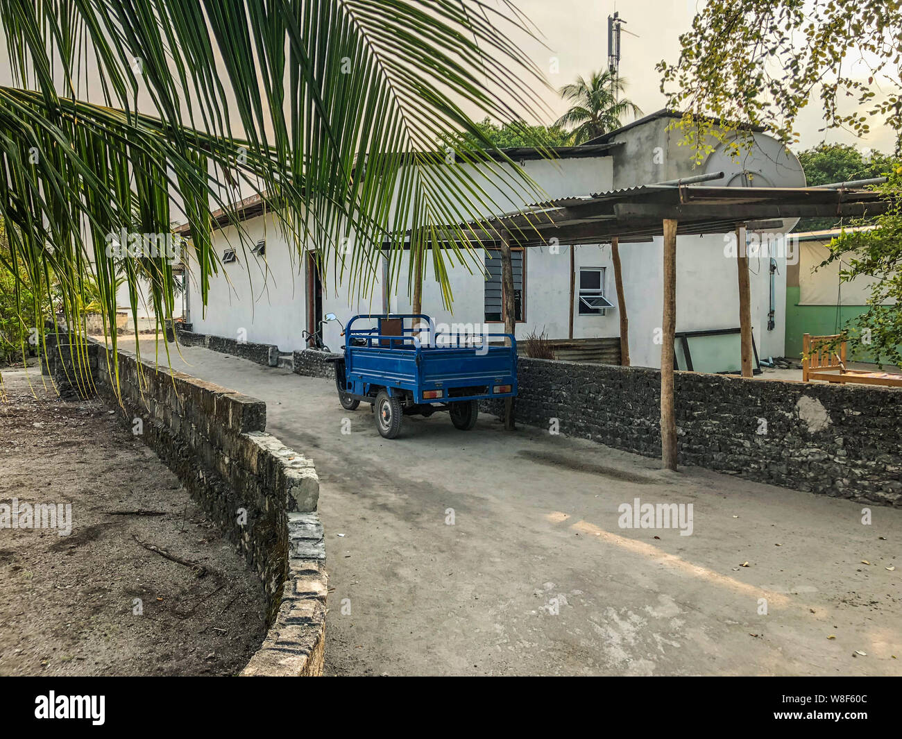 Empty street in traditional Maldivian village with cargo motor tricycle ...