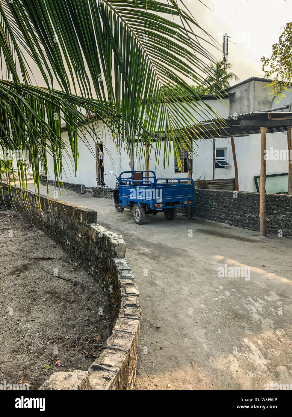 Empty street in traditional Maldivian village with cargo motor tricycle ...