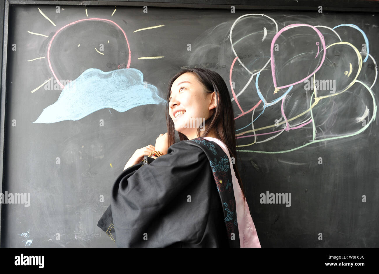 A Chinese graduates dressed in an academic gown poses for graduation ...