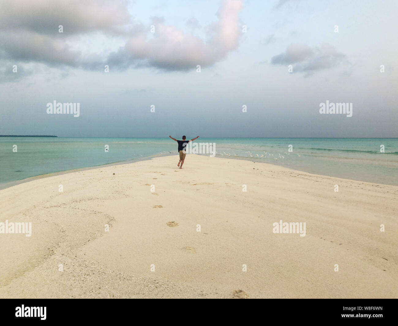 A young man is running along the beach on sandbank, Maldives Stock ...