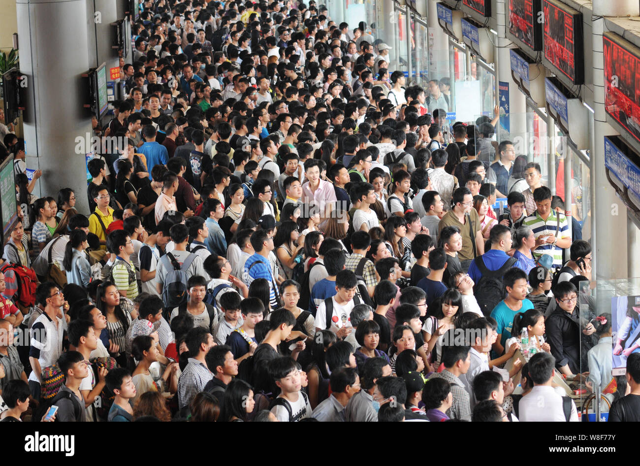 A crowd of passengers queue up in the hall of a long-distance bus ...