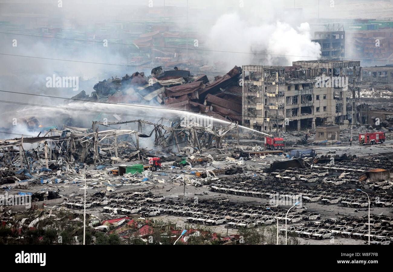 Chinese firefighters hose water to extinguish fire next to burnt cars ...