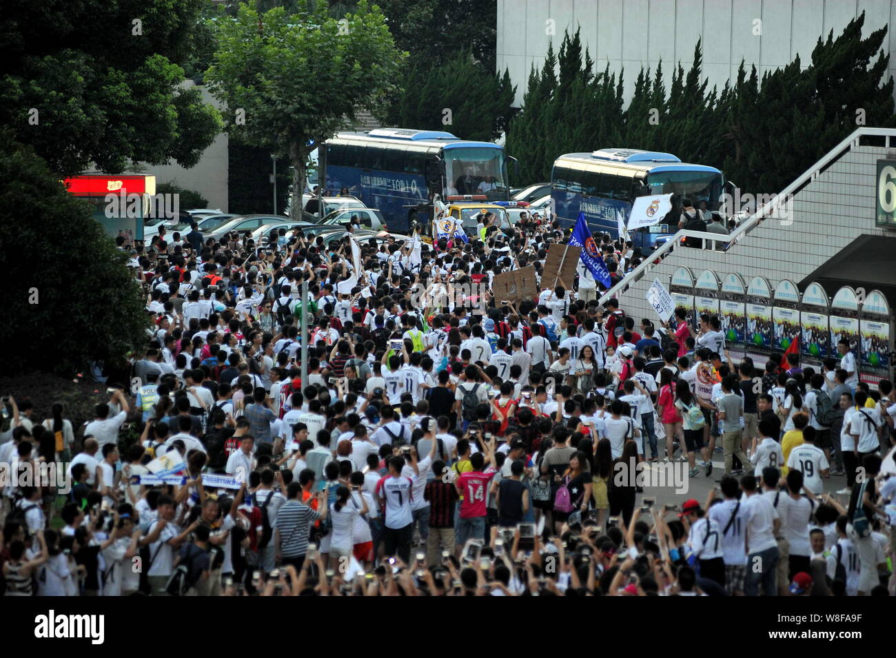 A crowd of football fans watch the arrival of buses carrying players of ...