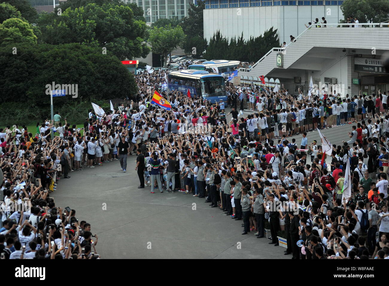 A crowd of football fans watch the arrival of buses carrying players of ...