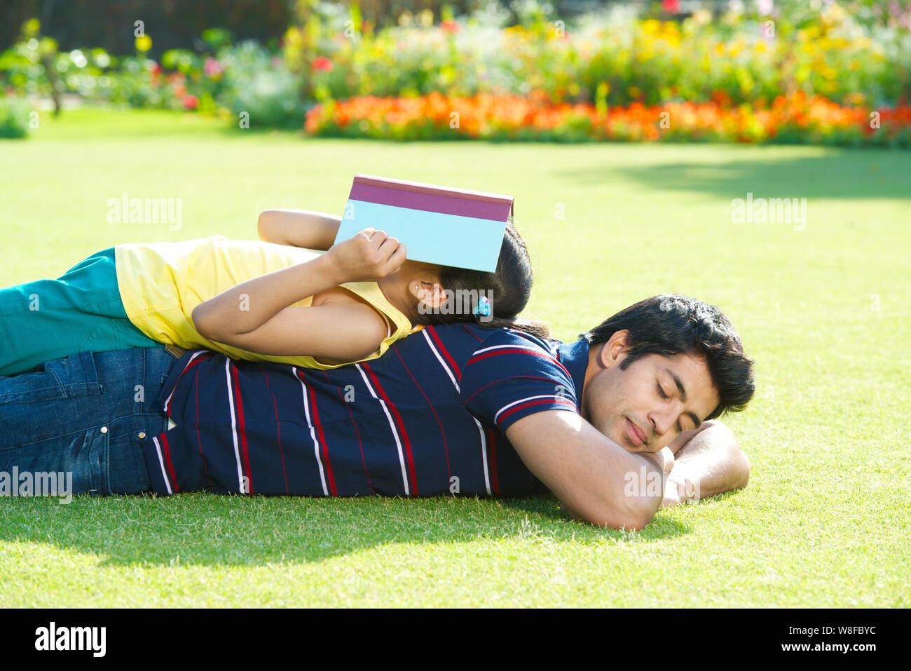 Man lying in a park with his daughter napping Stock Photo - Alamy