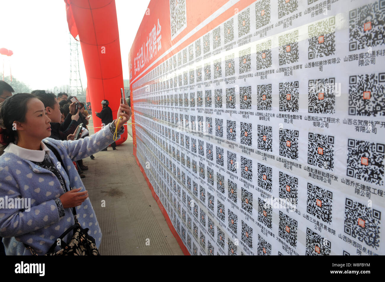 Job seekers scan QR codes on a big billboard of available jobs to ...