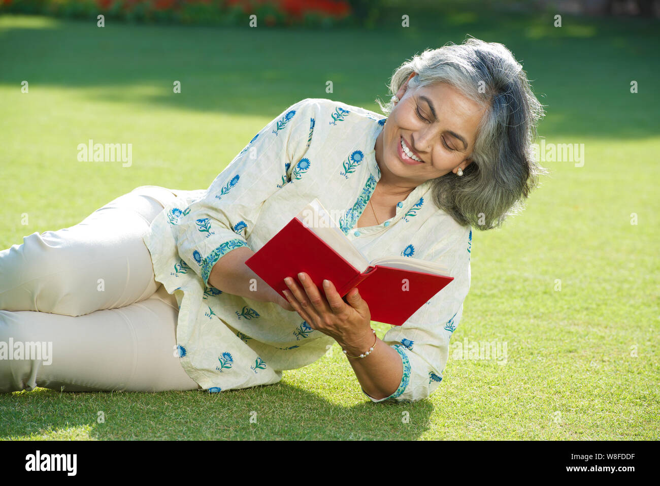 Senior woman reading a book in lawn Stock Photo - Alamy