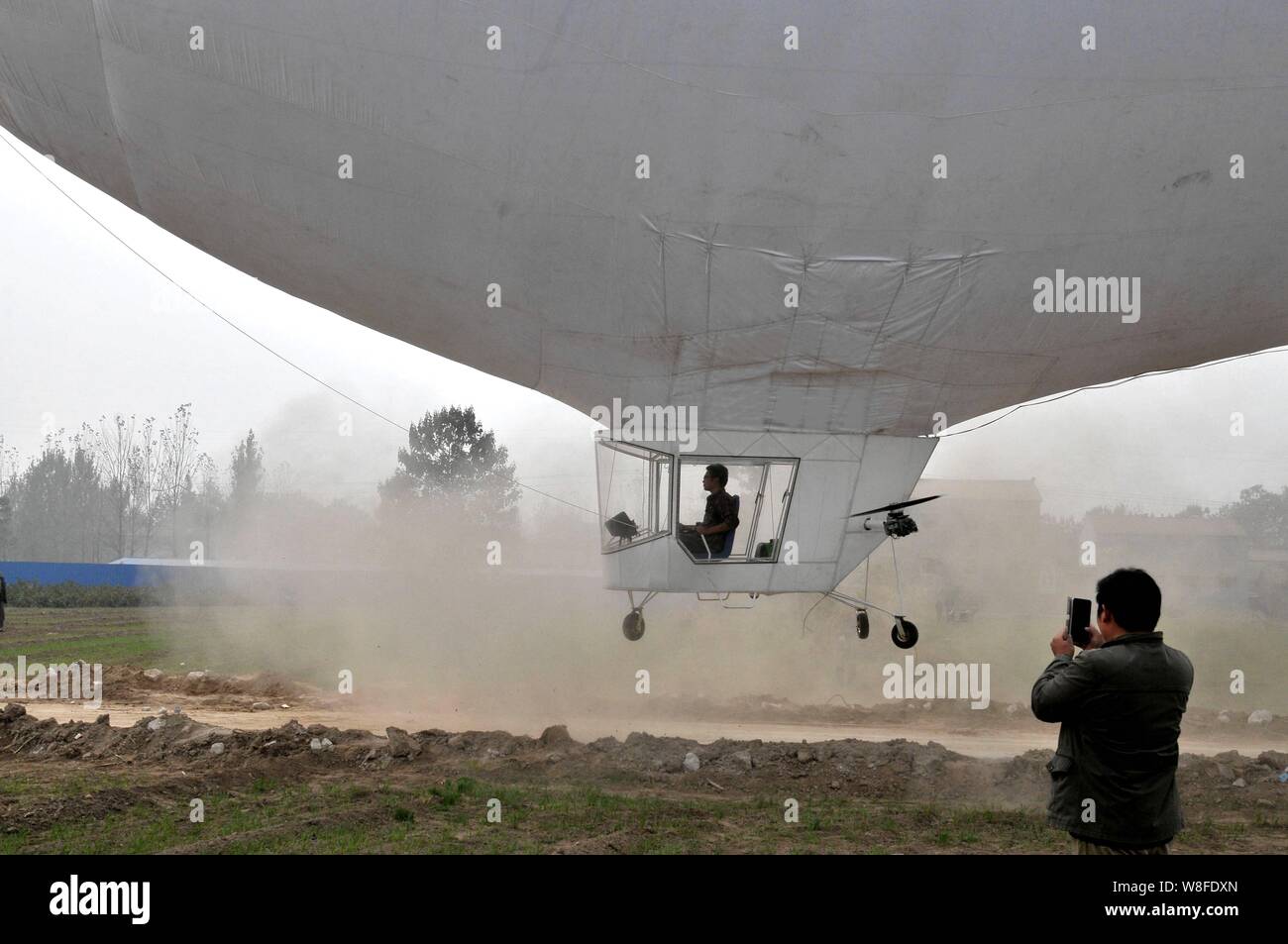 A villager takes photos of the zeppelin made by Chinese farmer Shi ...