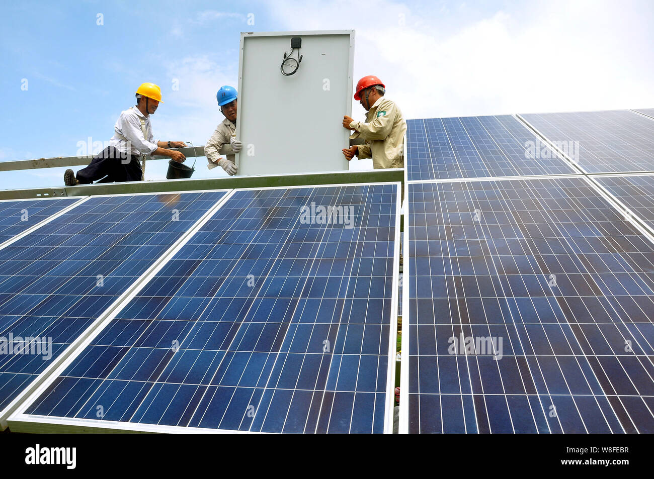 --FILE--Chinese workers install solar panels at a photovoltaic power ...